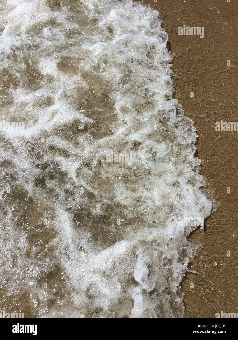 Foam waves by the shore on the beach Stock Photo - Alamy