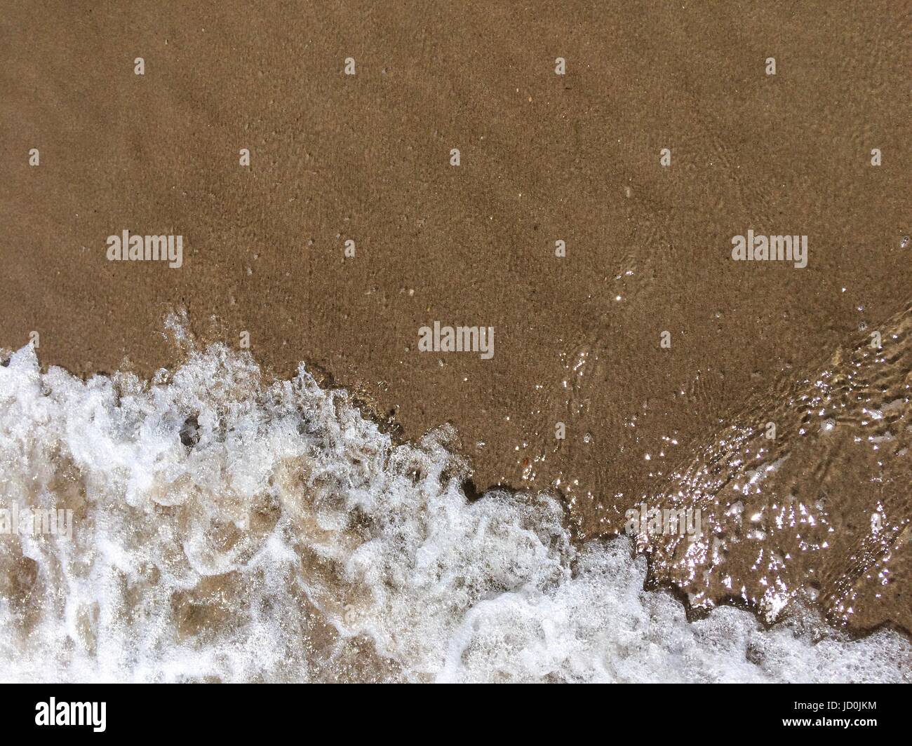Foam waves by the shore on the beach Stock Photo - Alamy