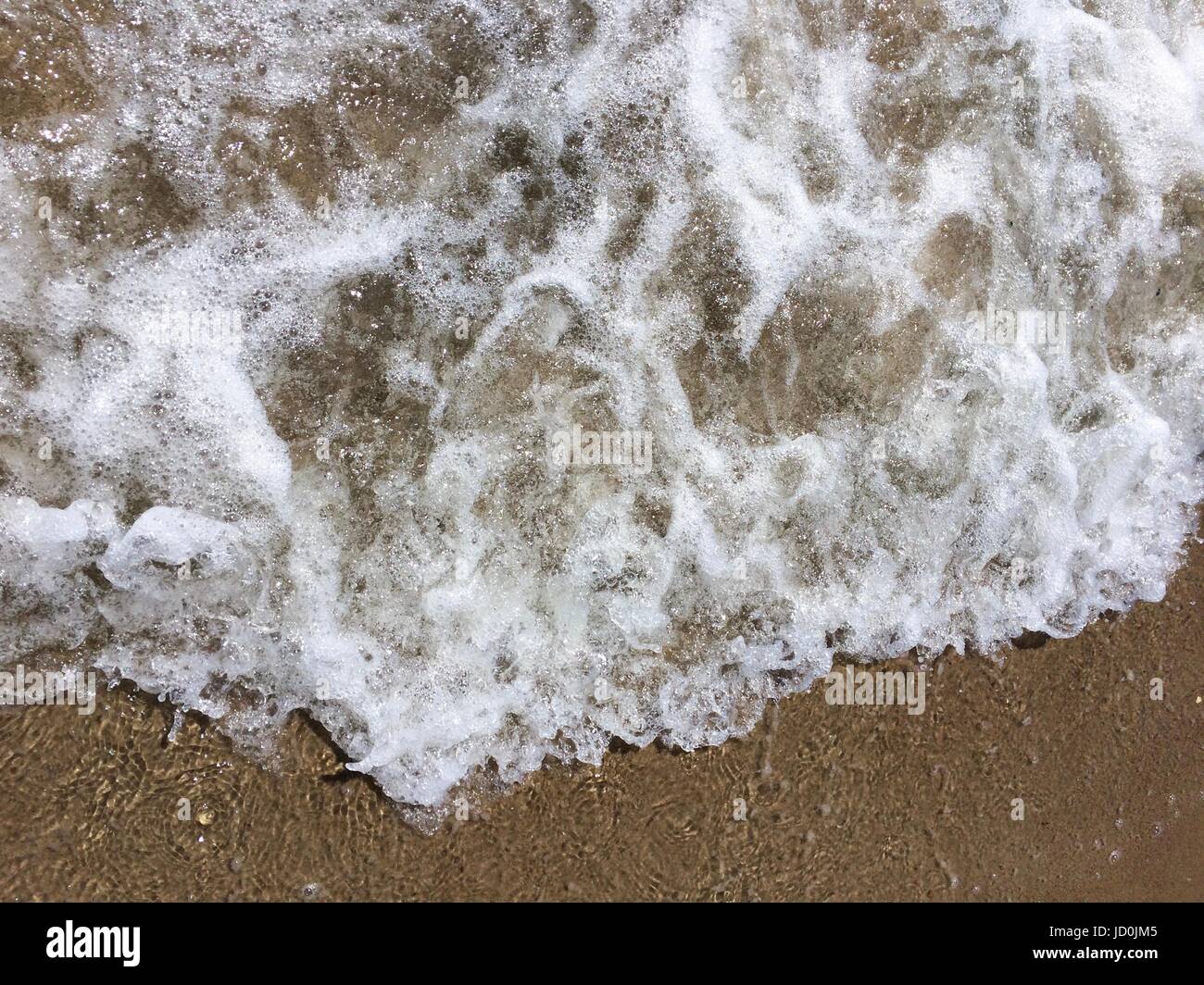 Foam waves by the shore on the beach Stock Photo - Alamy