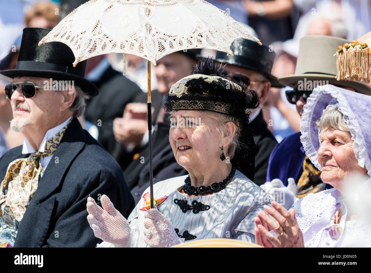 Three people sitting and clapping, all seniors, two women and one man ...