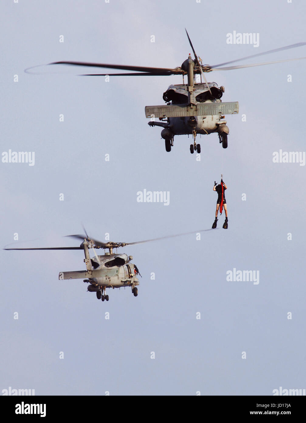 A Navy SH-60H Seahawk helicopter hoists a Navy rescue swimmer from the ...