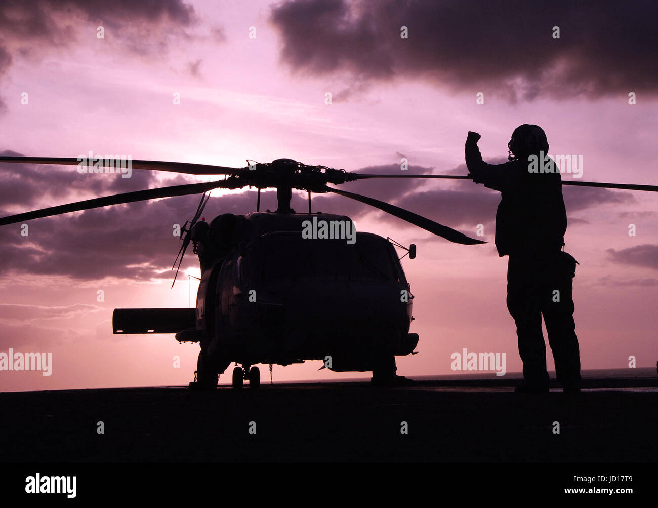 A flight deck crewman signals to the pilot of an MH-60 Seahawk ...