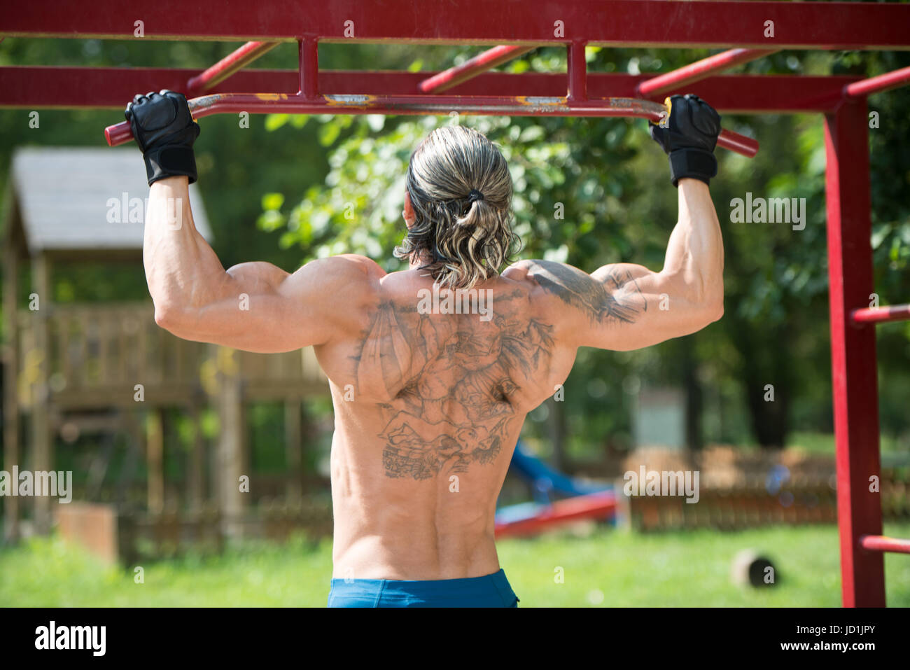 Muscular Built Athlete Working Out In An Outdoor Gym - Doing Chin-Ups ...