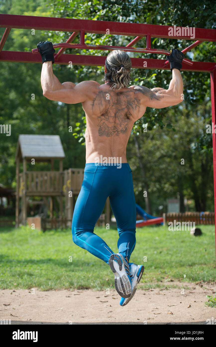 Muscular Built Athlete Working Out In An Outdoor Gym - Doing Chin-Ups ...