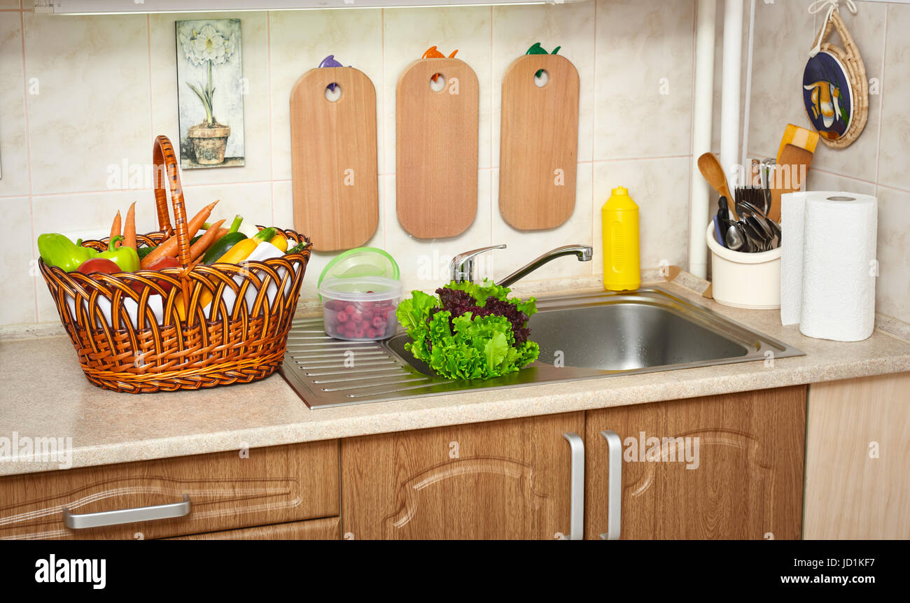 vegetables and fresh greens in basket in kitchen interior, healthy food ...