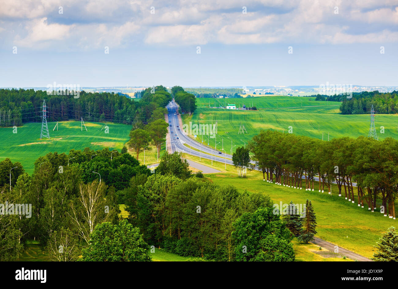 Green fields, trees, road and sky with clouds. Summer landscape. Minsk ...