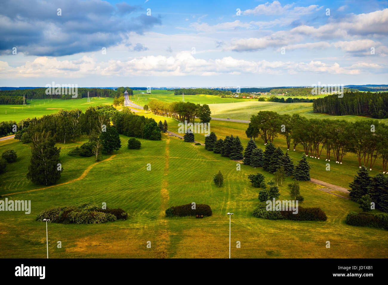 Green fields, meadows, trees, road and blue sky with clouds. Bright ...