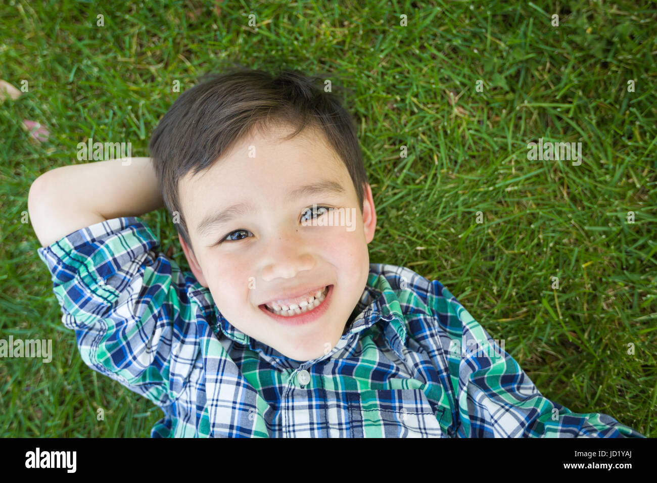Mixed Race Chinese and Caucasian Young Boy Relaxing On His Back Outside ...