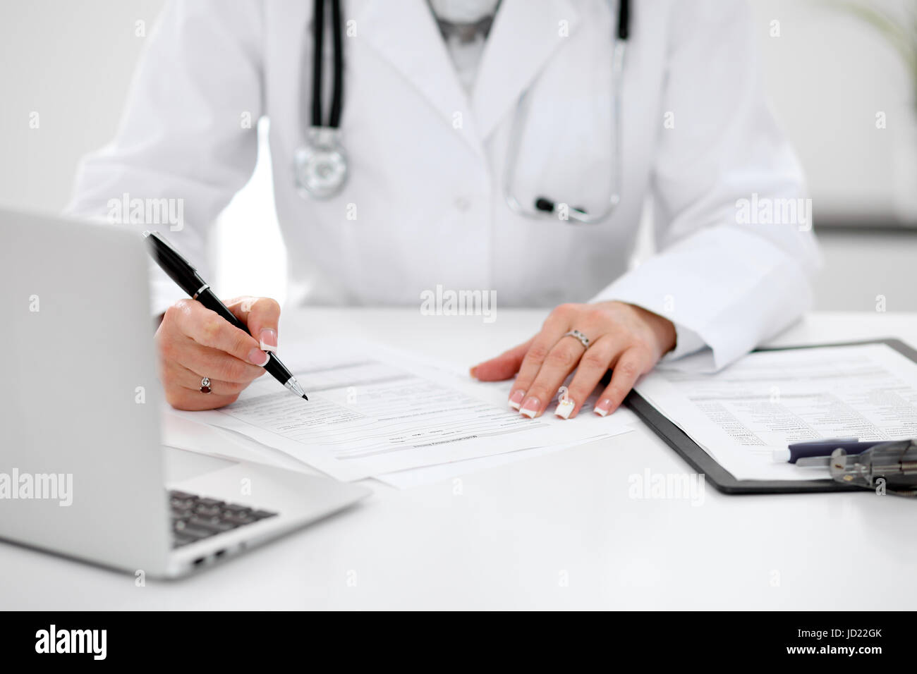 Close-up of a female doctor filling out application form , sitting at ...