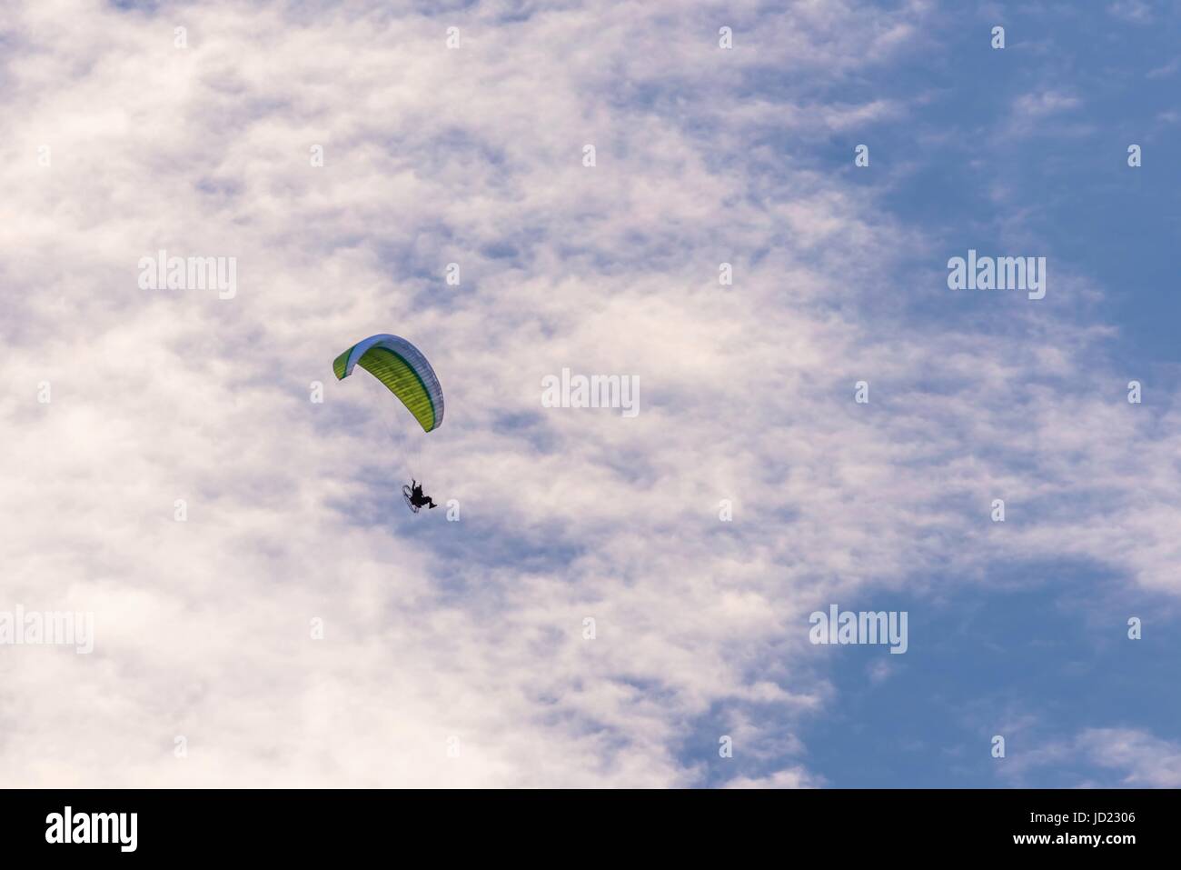 Horizontal photo of single paraglider with green / white wings and ...