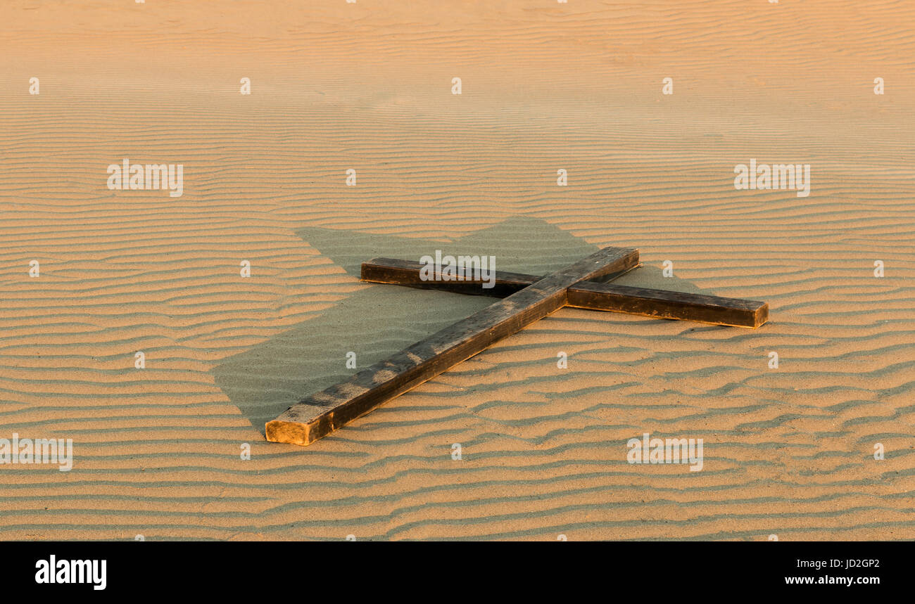 Wooden black cross laying down on waves of sand Stock Photo - Alamy