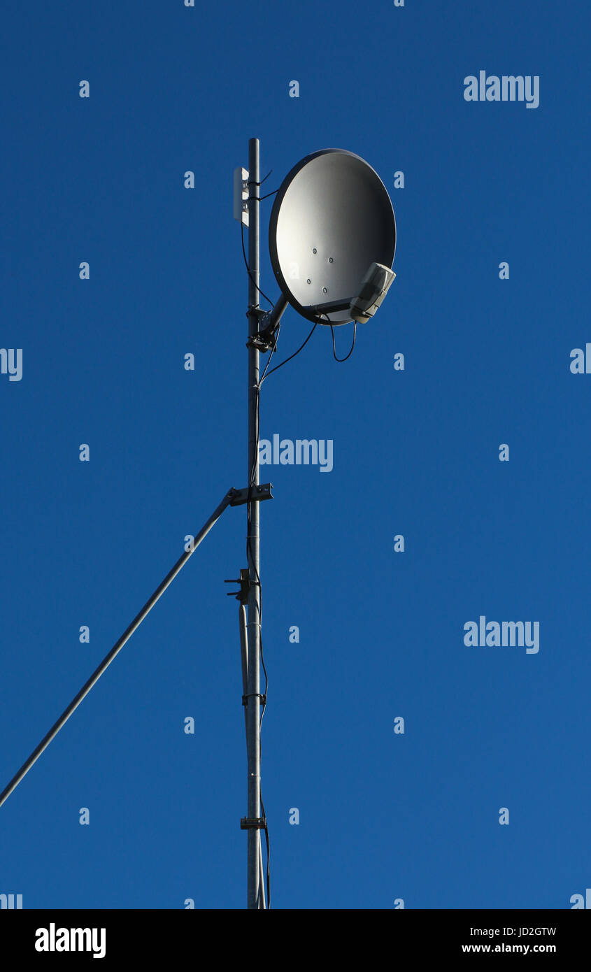 Satellite dish on a pole with a blue sky background Stock Photo - Alamy