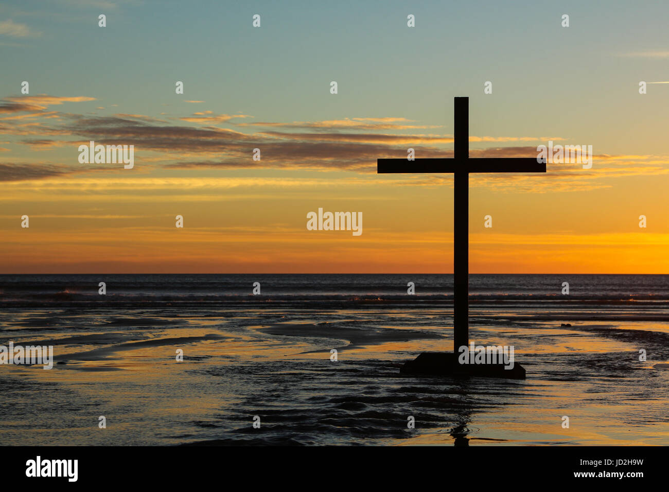 Cross at sunset with water from a stream pass the cross to the sea ...