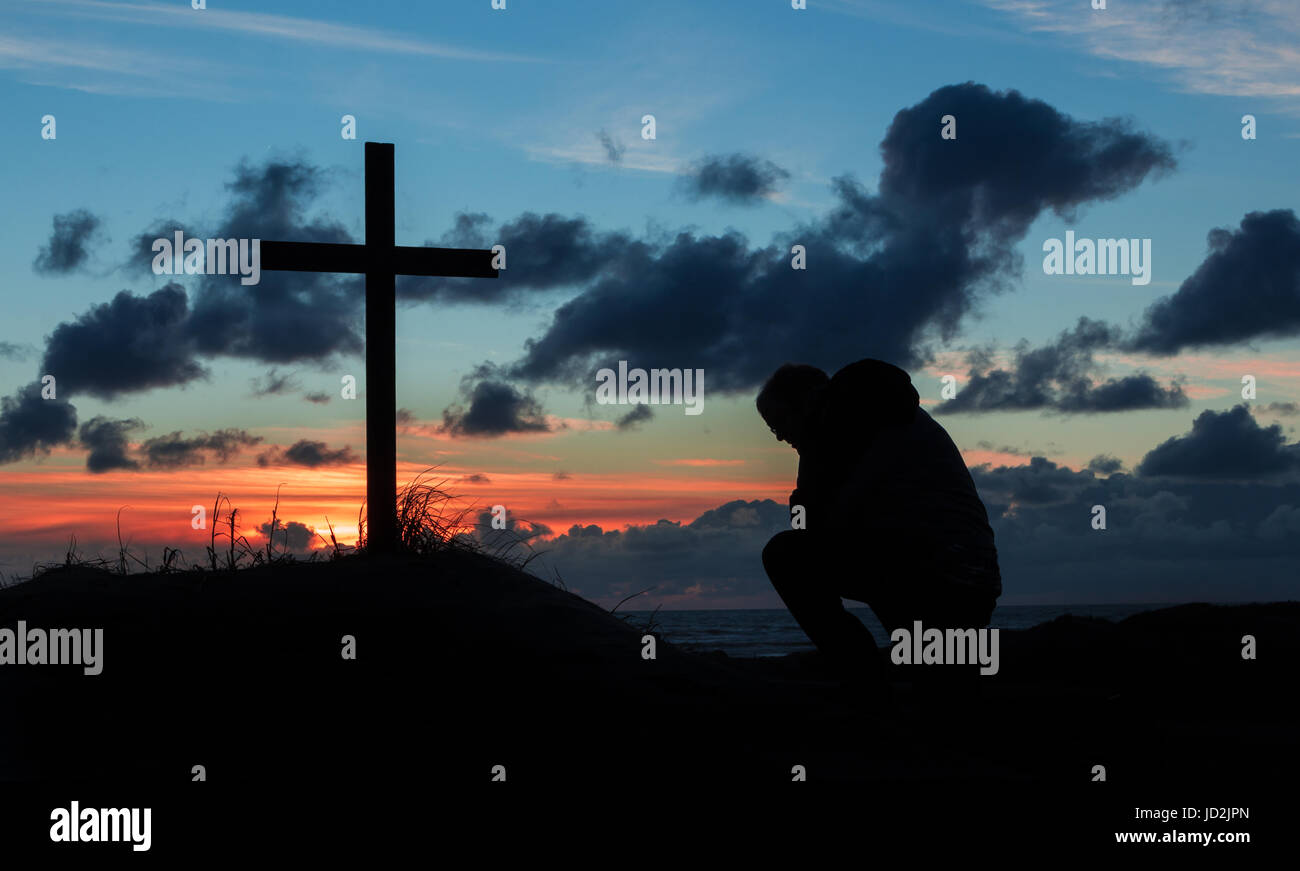 Person Praying On Knees At Cross