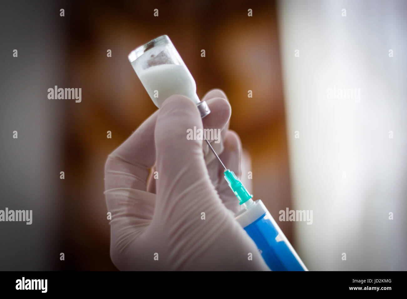 Young doctor prepares an injection to a patient, the injected liquid in ...