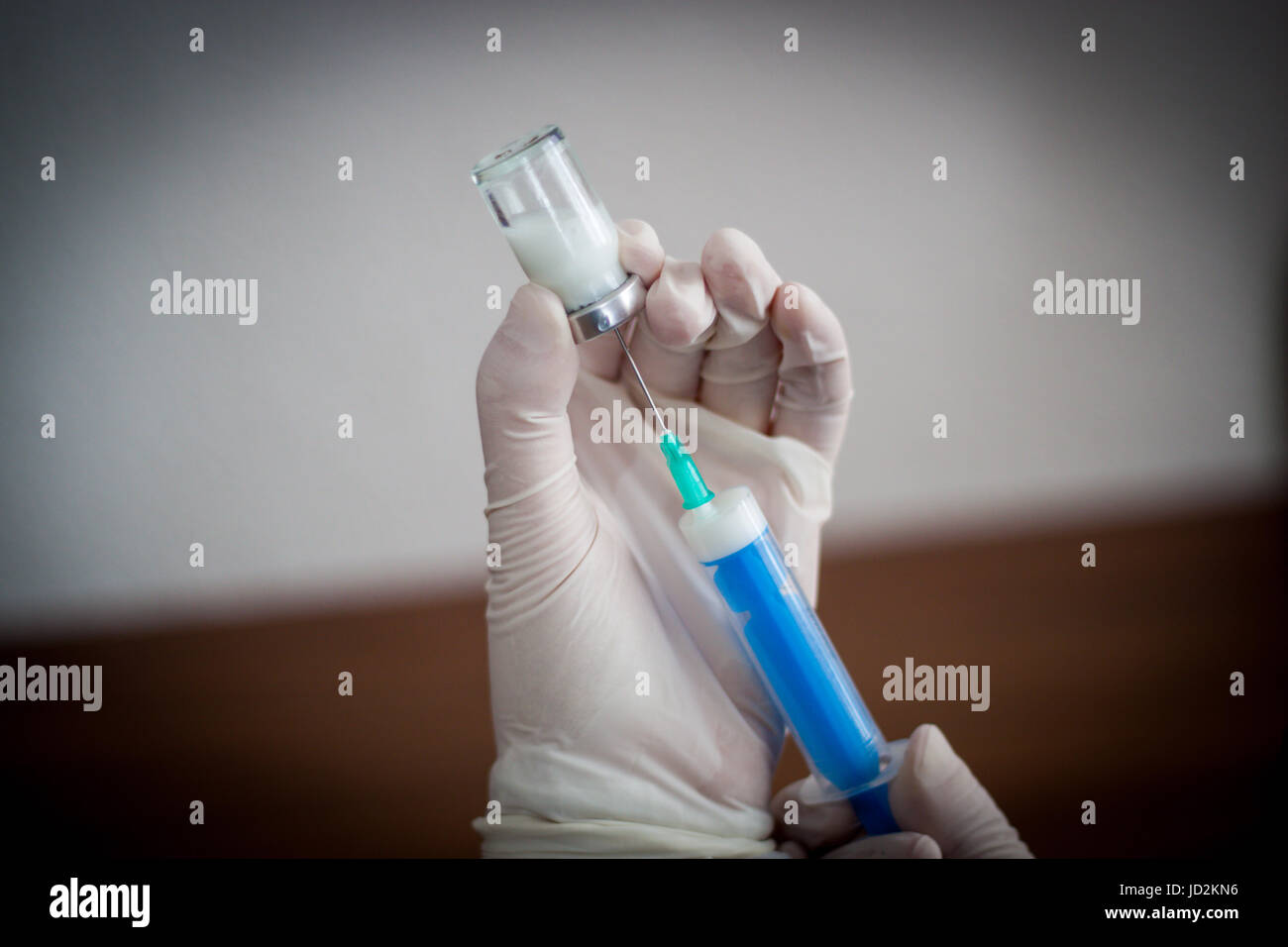 Young doctor prepares an injection to a patient, the injected liquid in ...