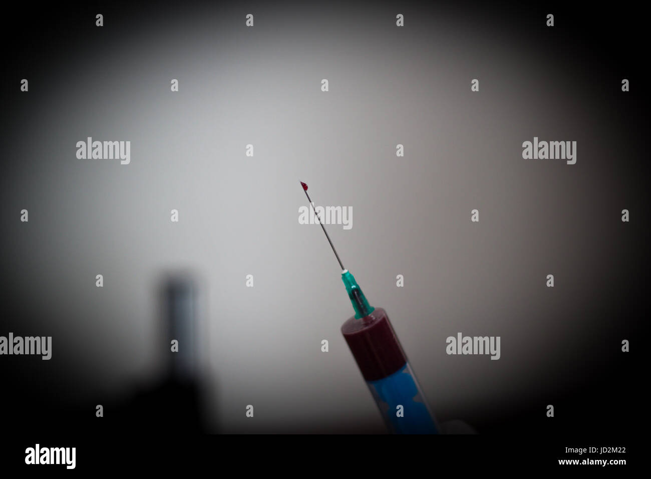 Doctor holding a needle in his hand in which he has blood on the tip of ...