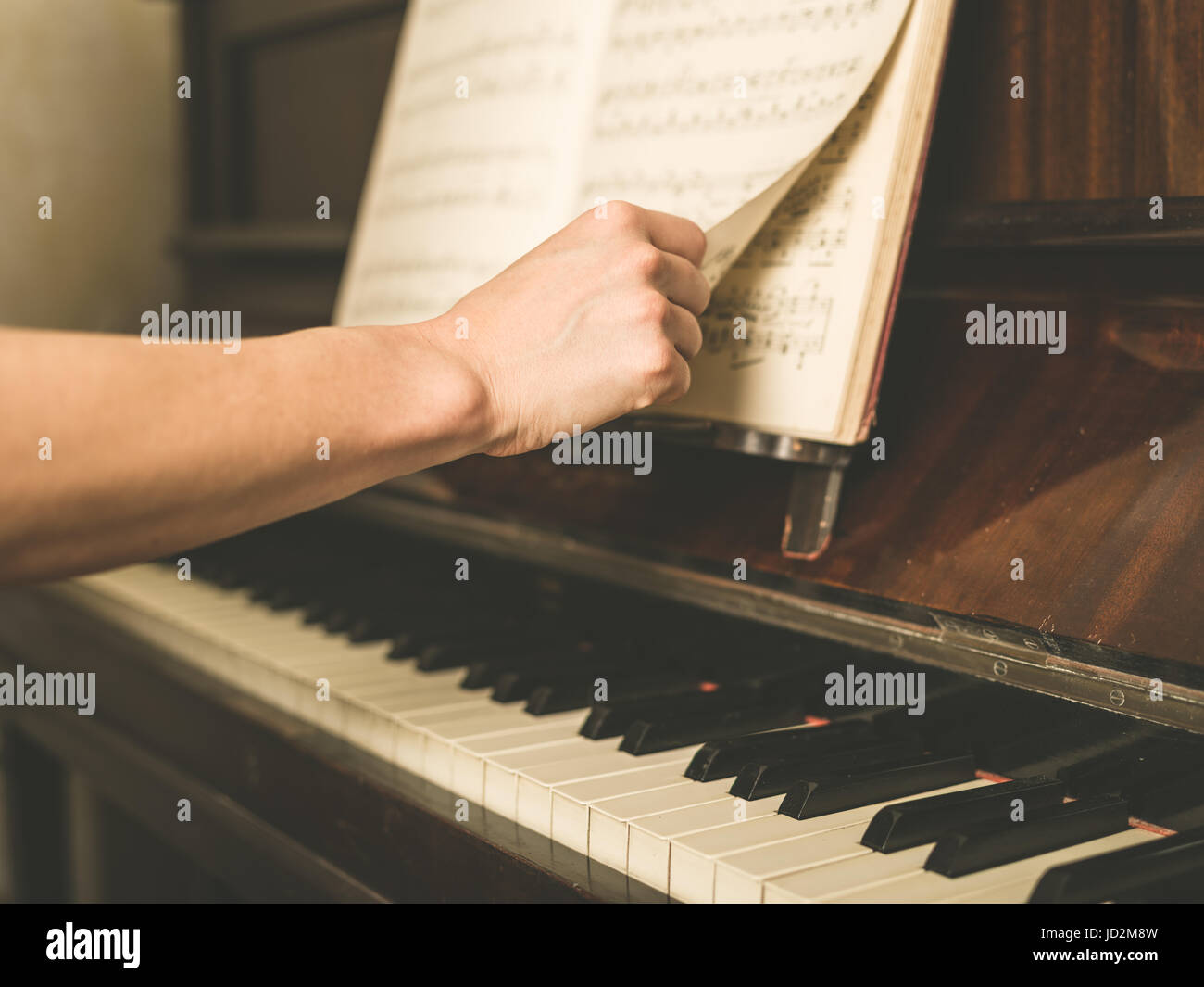 The hand of a young woman is turning music paper at a piano Stock Photo ...