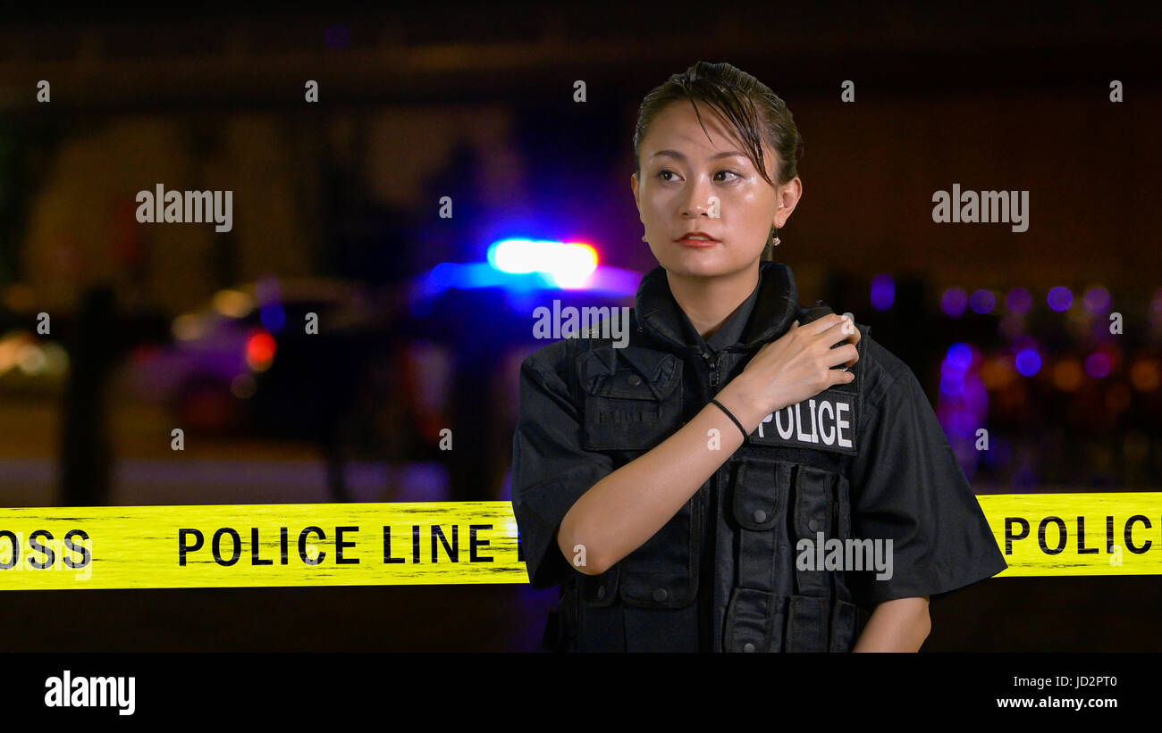 Asian American Policewoman using police radio with siren and boundary ...