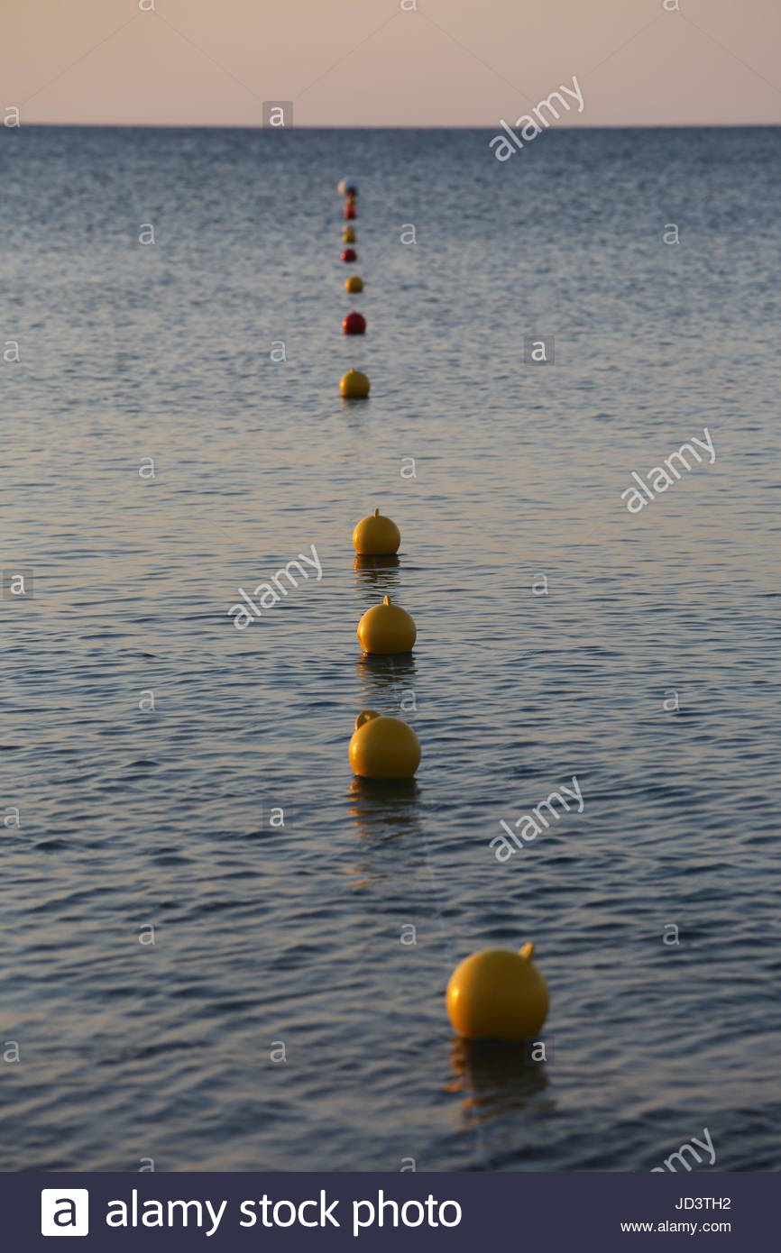 A line of yellow buoys on the water at dawn off the coast of Rhodes in ...