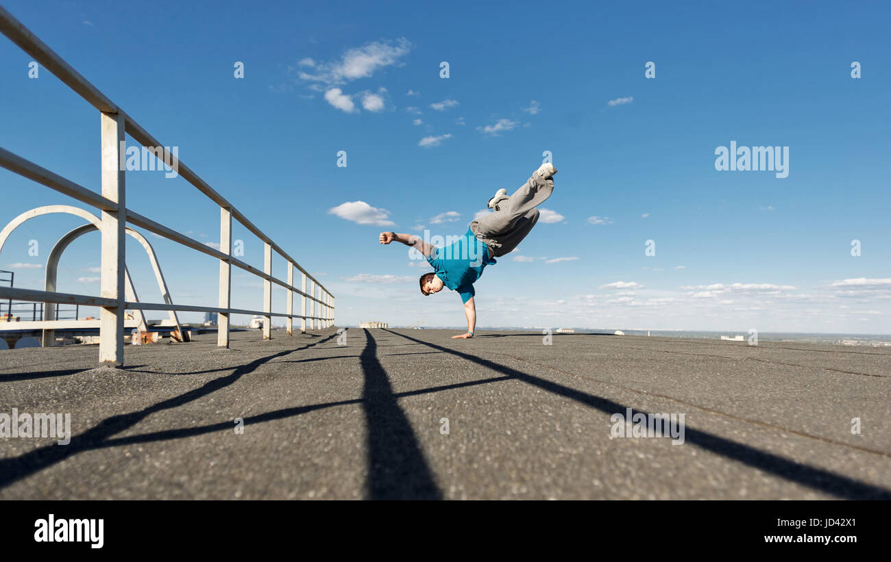 Roofer stands on hands on the edge of the roof. Extreme acrobatics ...