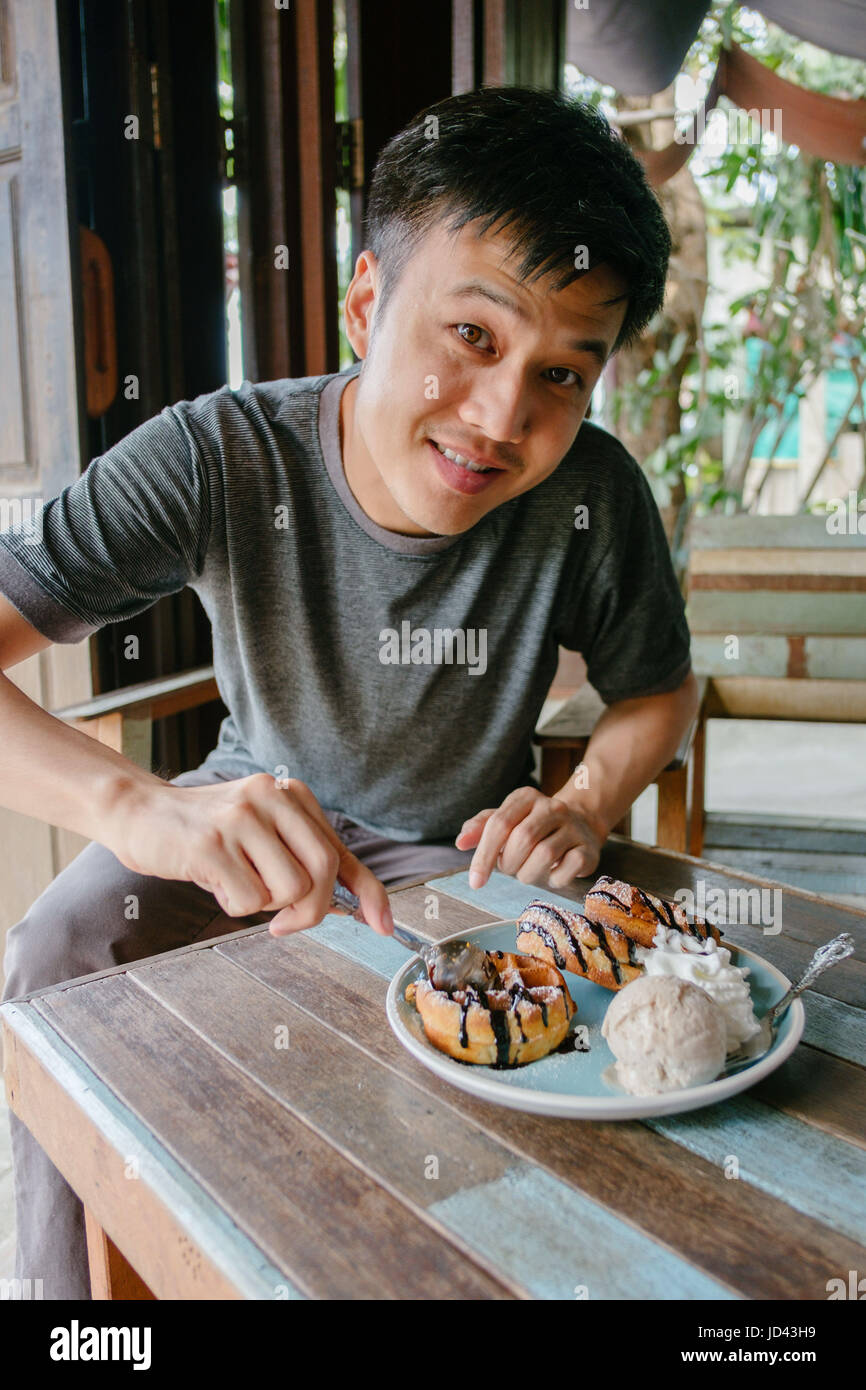 Man smiling eating waffle with ice-cream at vintage cafe Stock Photo ...