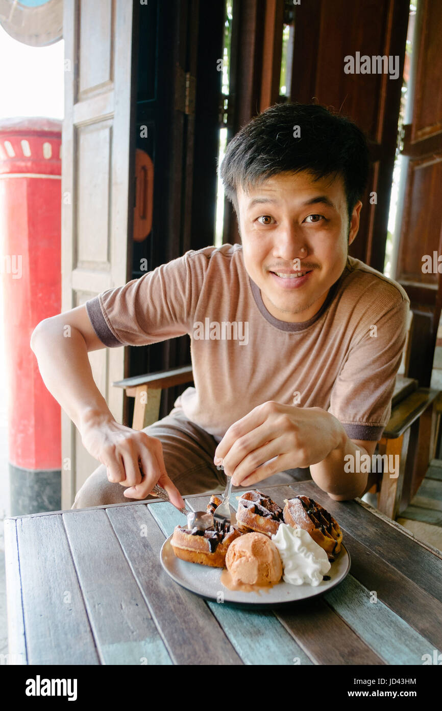 Man smiling eating waffle with ice-cream at vintage cafe Stock Photo ...