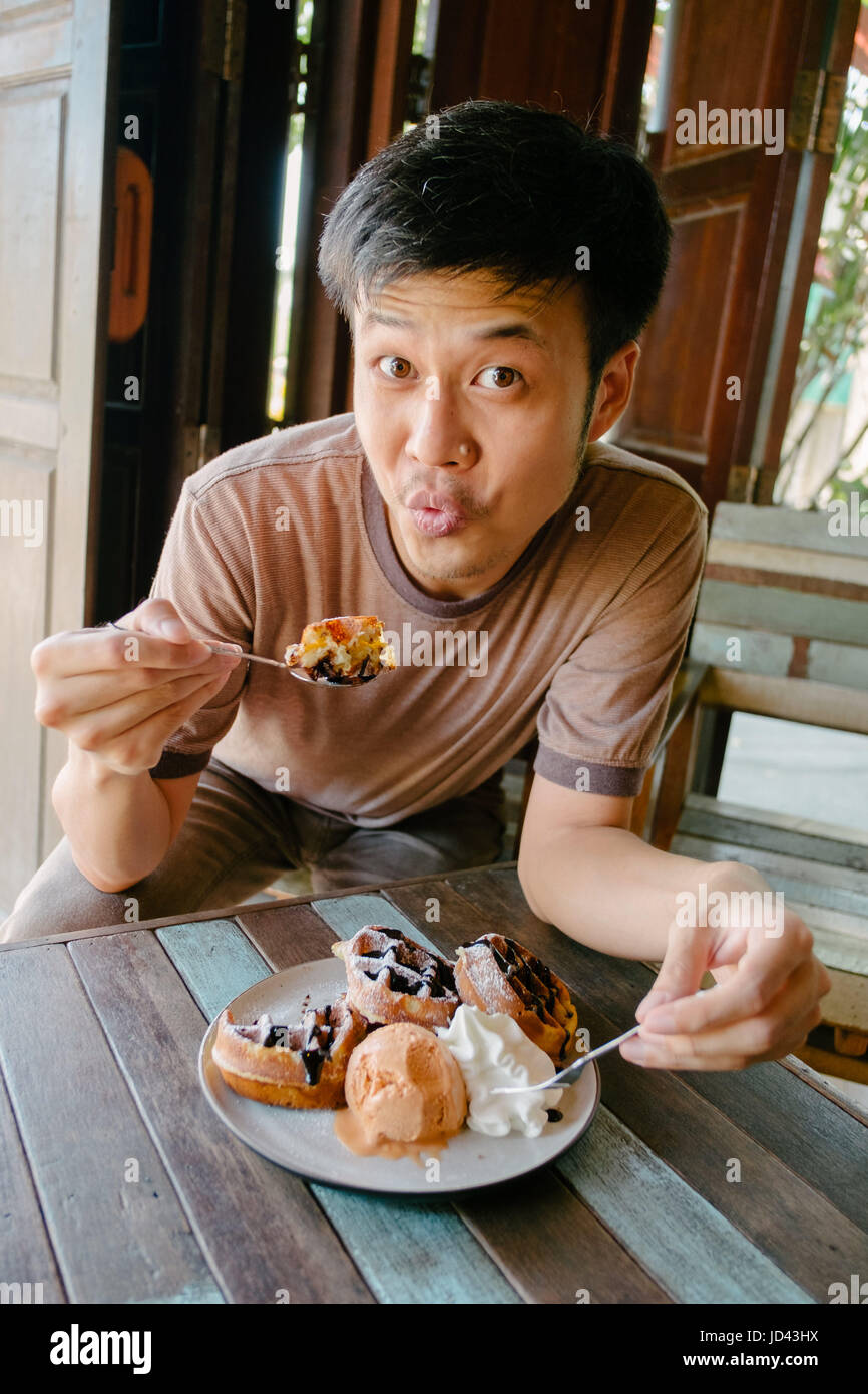 Man smiling eating waffle with ice-cream at vintage cafe Stock Photo ...