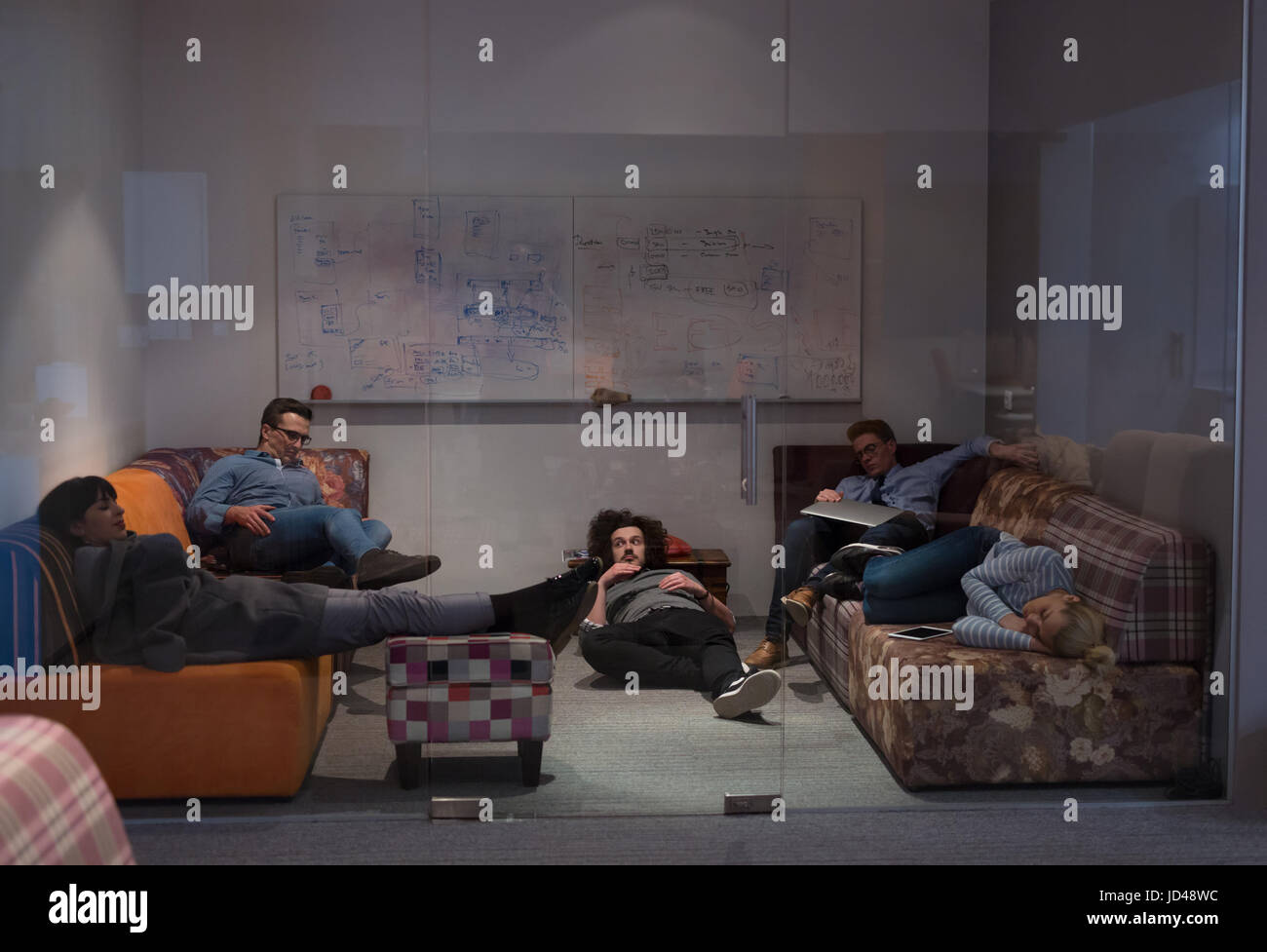 group of young casual software developer sleeping on sofa during a work ...