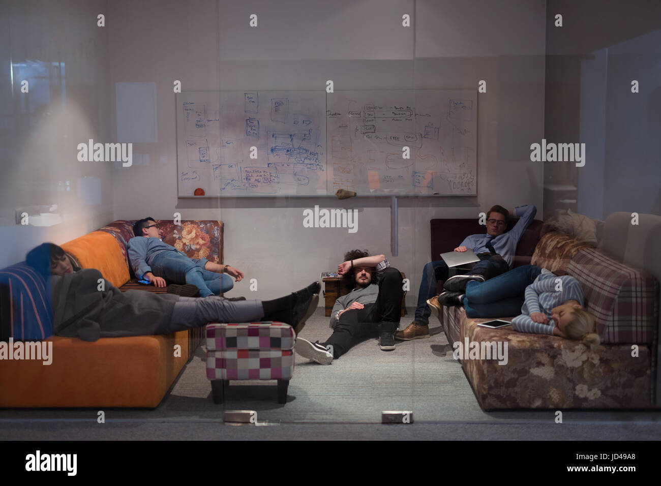 group of young casual software developer sleeping on sofa during a work ...