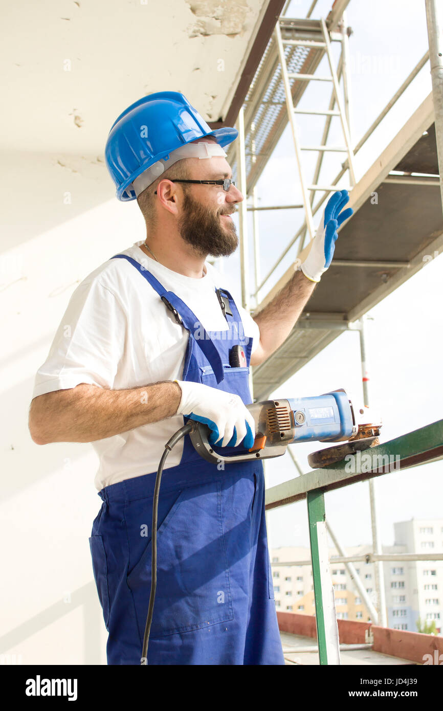 Smiling construction worker in a working outfit and in a protective ...