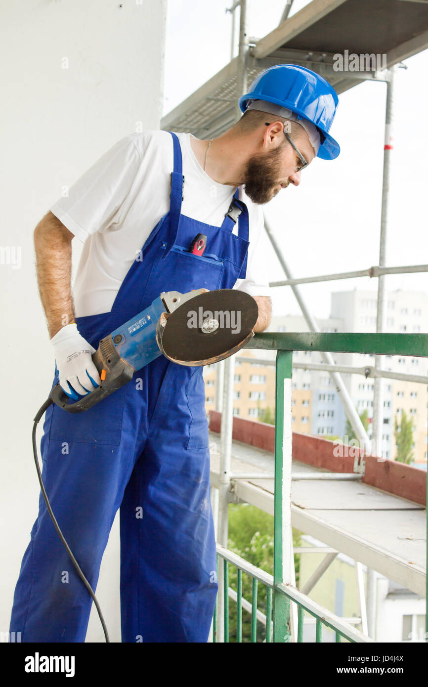 Construction worker in working outfit and in protective helmet stands ...