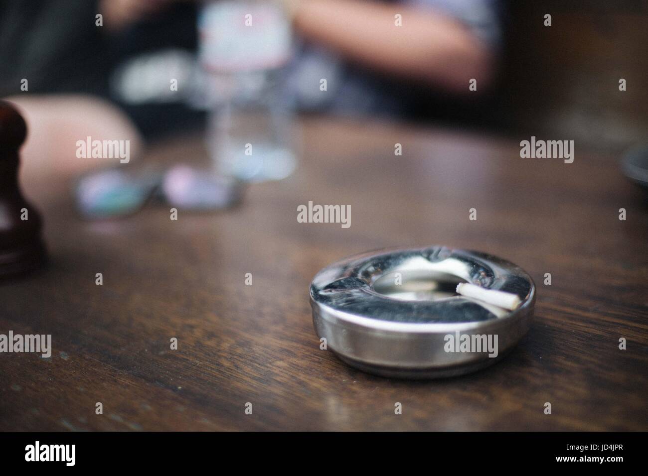 Photograph of a cigarette in an ashtray on a wooden table Stock Photo ...