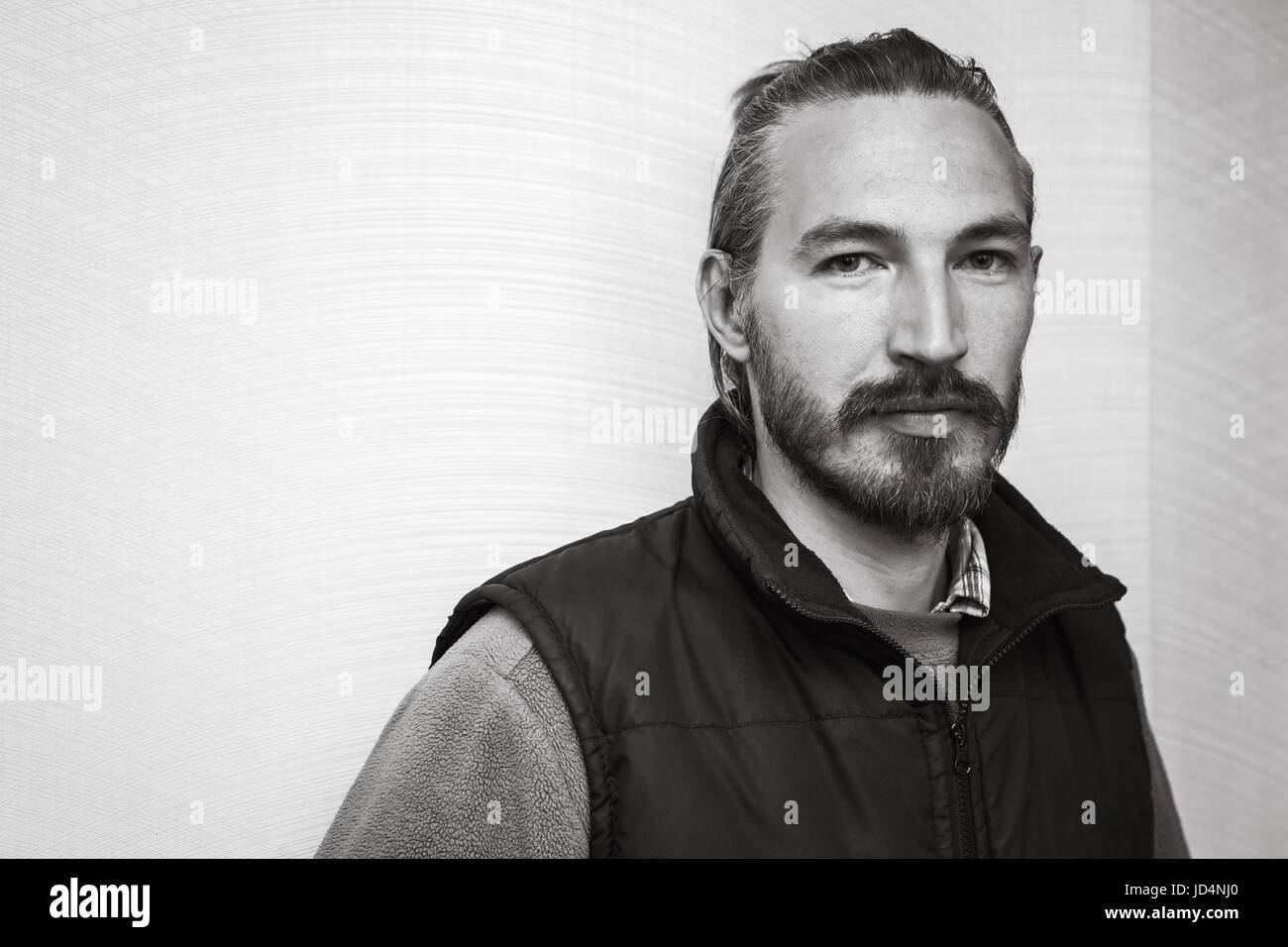Black and white portrait of young bearded Asian man above light gray ...