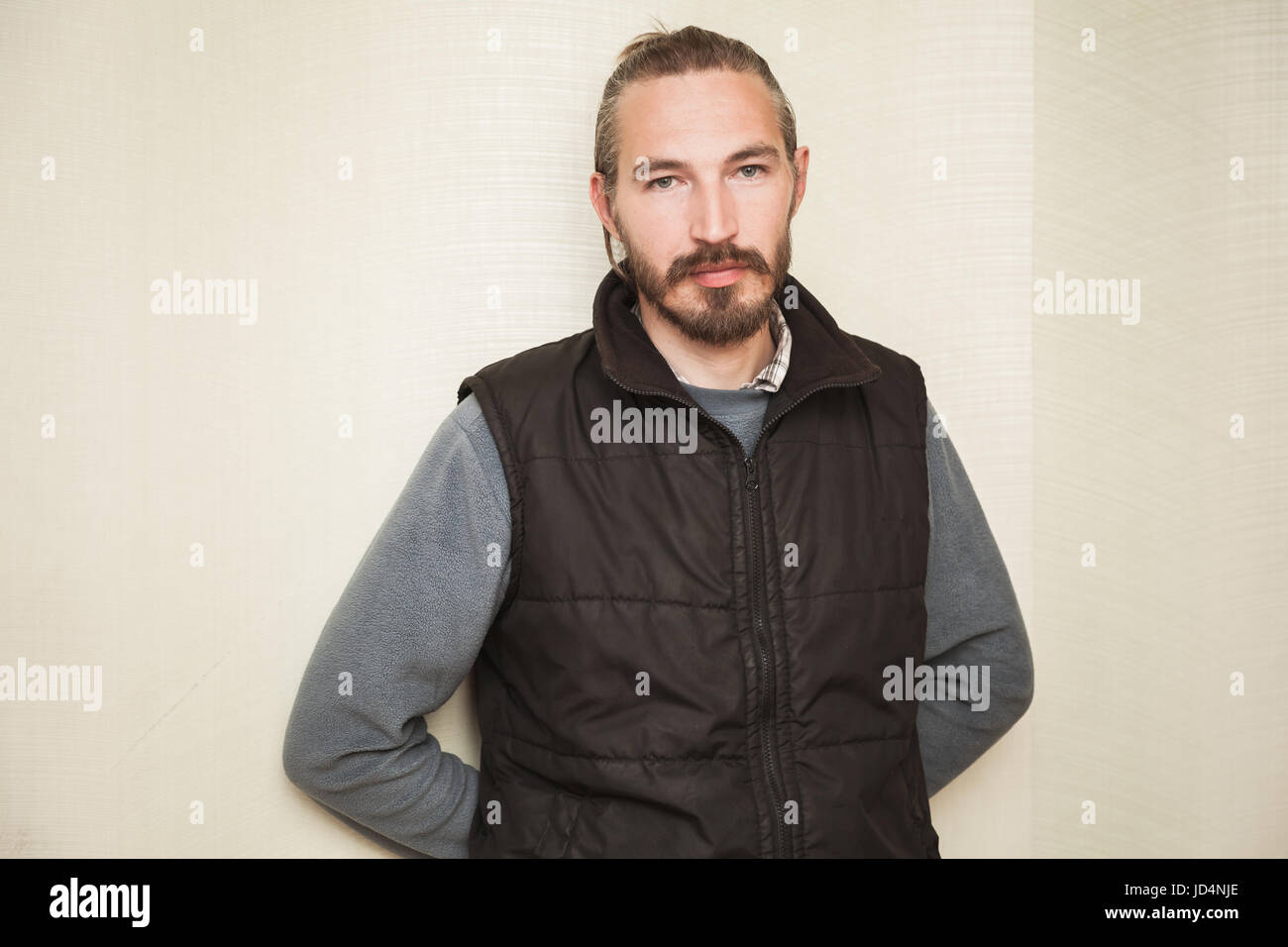Studio portrait of young bearded Asian man over gray wall background ...