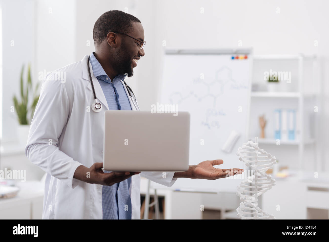 Happy smart doctor pointing at the DNA model Stock Photo - Alamy