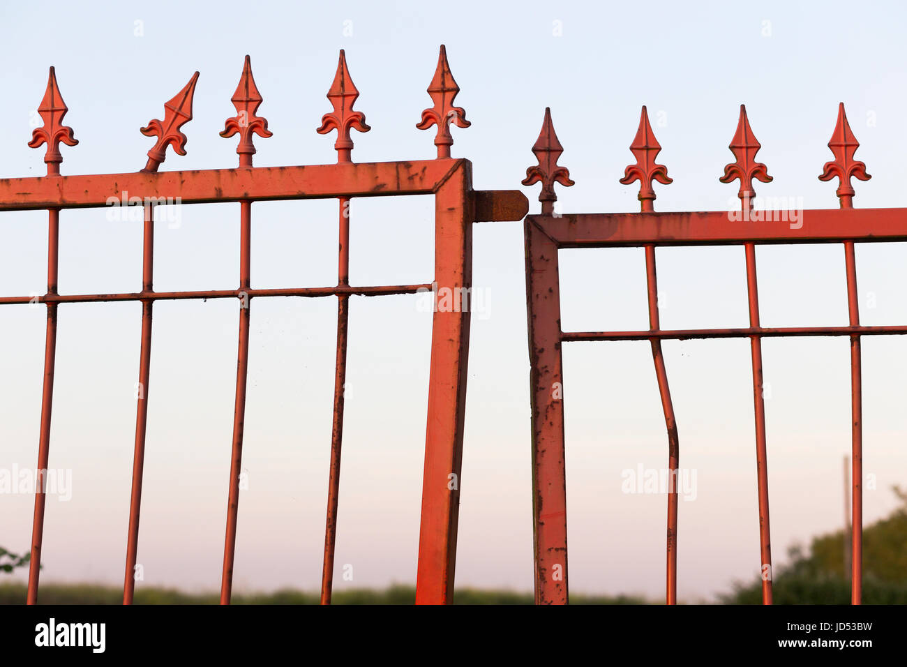 Red-painted rusty and bent steel gate with finials Stock Photo - Alamy