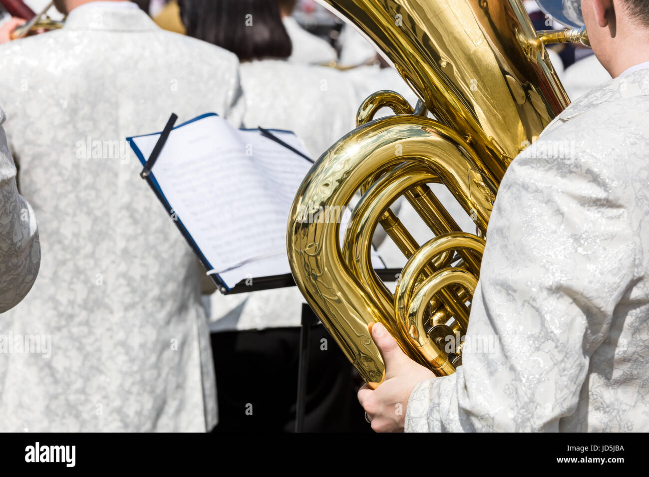 tuba player at brass band with musical notes on stand during open air ...