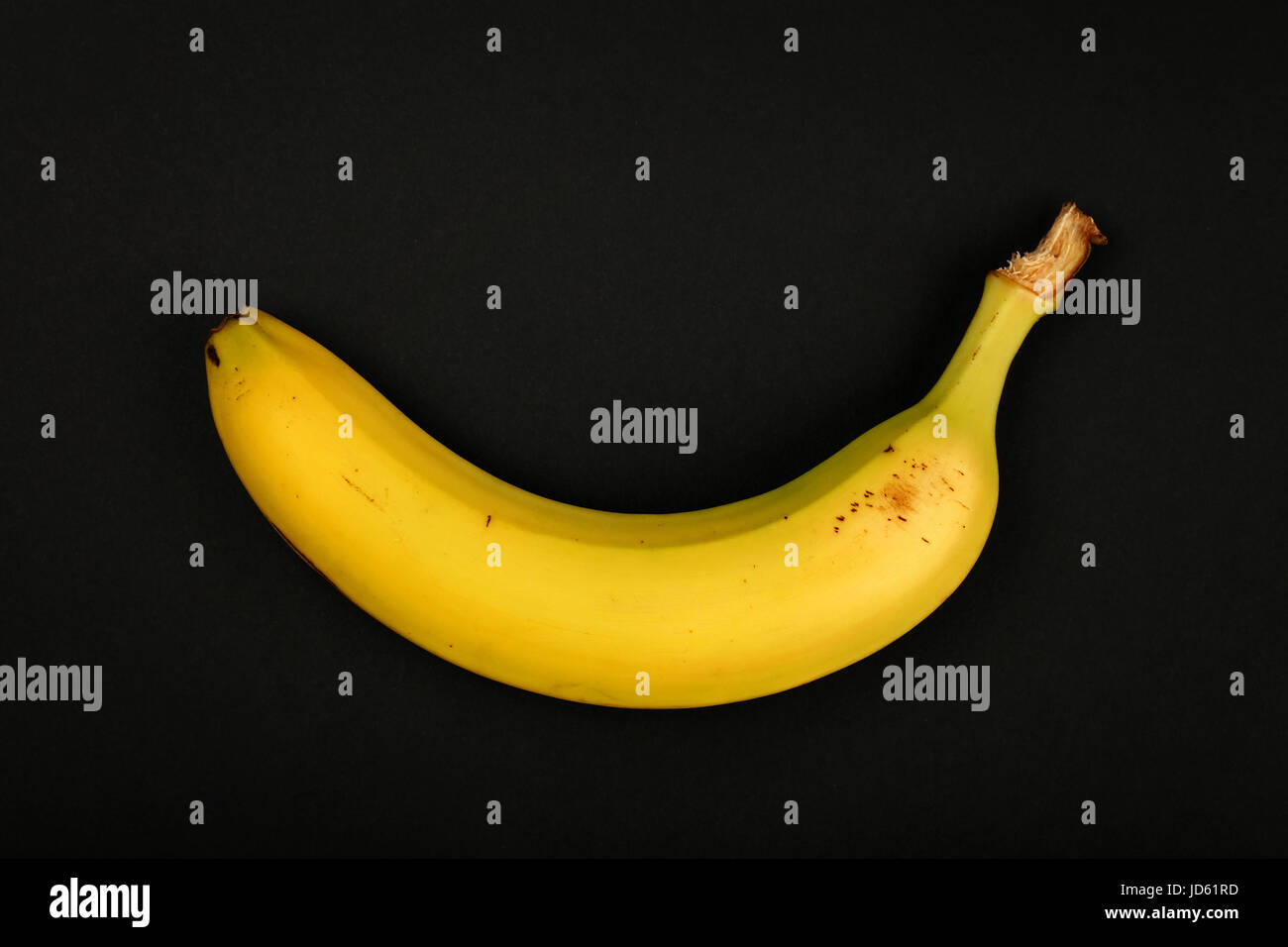 One fresh ripe yellow banana isolated on black paper background, close ...