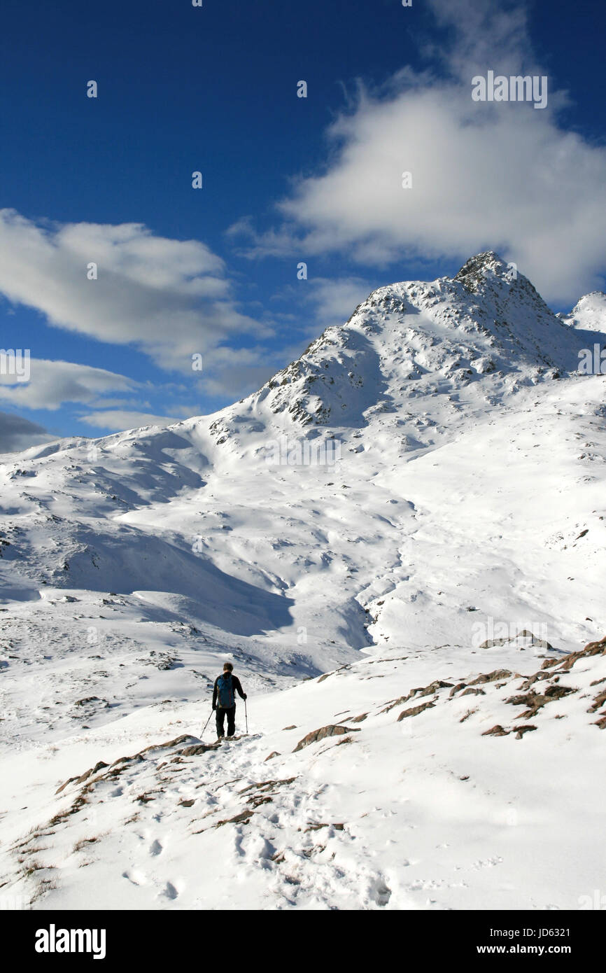 Scottish winter mountaineer walking towards the start of a snow covered ...