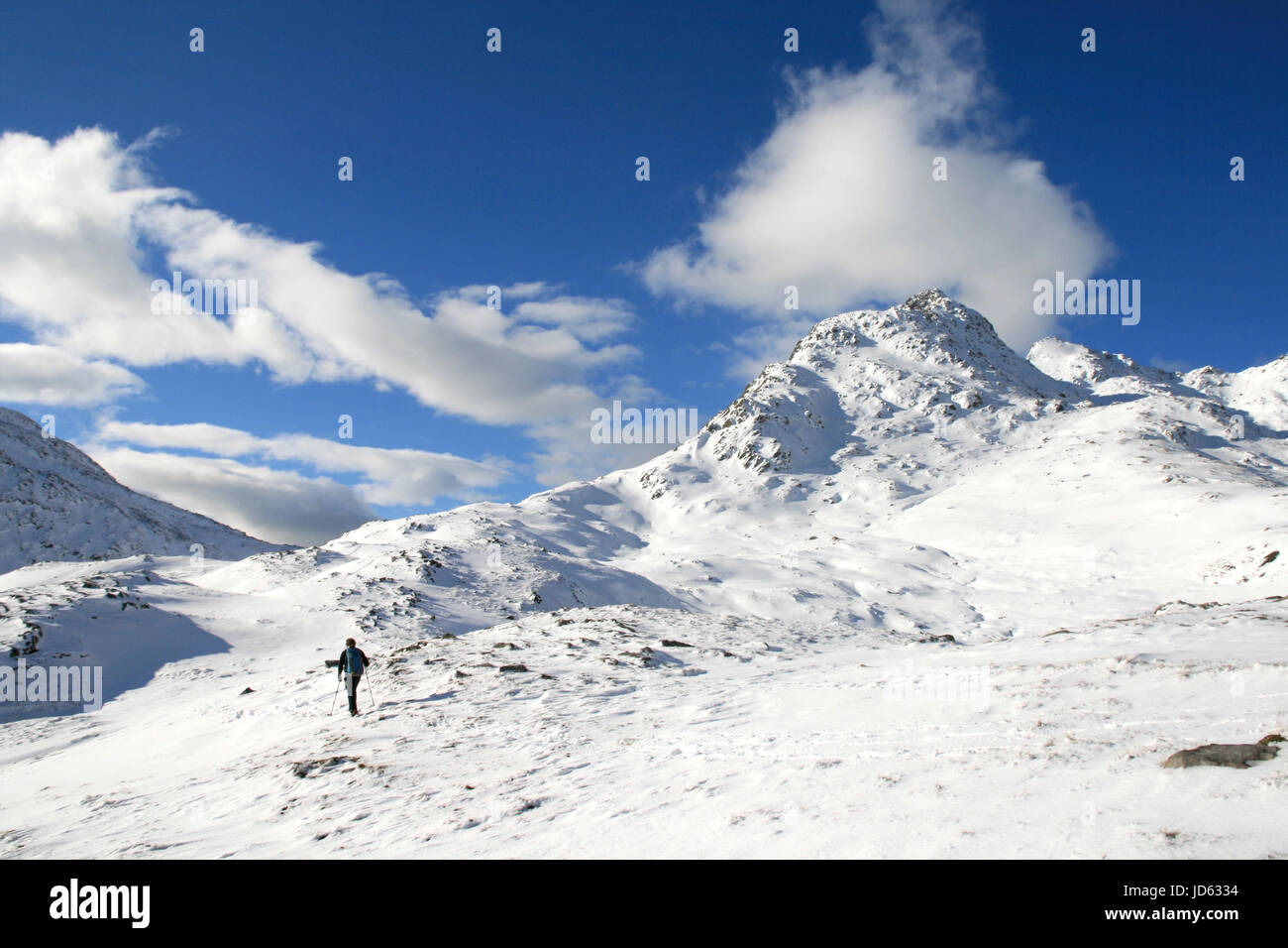 Scottish winter mountaineer walking towards the start of a snow covered ...