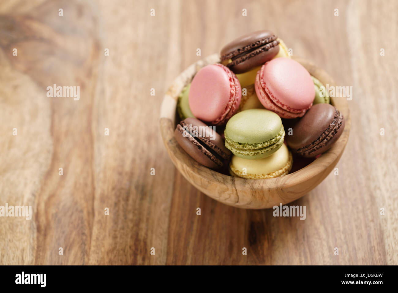 assorted macarons in wood bowl on wooden table Stock Photo - Alamy