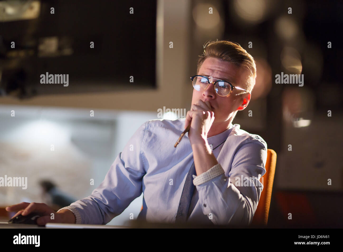 Young man working on computer at night in dark office. The designer ...