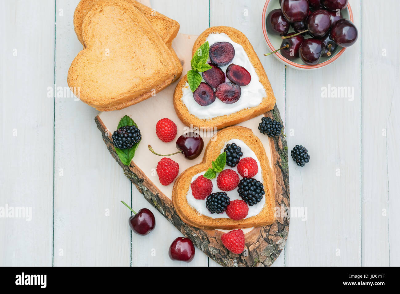 Bowl filled with cherries and heart shaped biscuits spread with quark ...