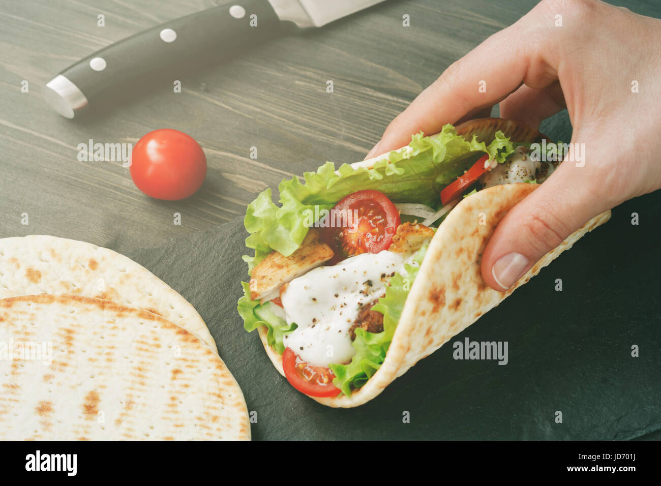 Hand holding mexican fajita wrap with chicken meat and vegetables ...