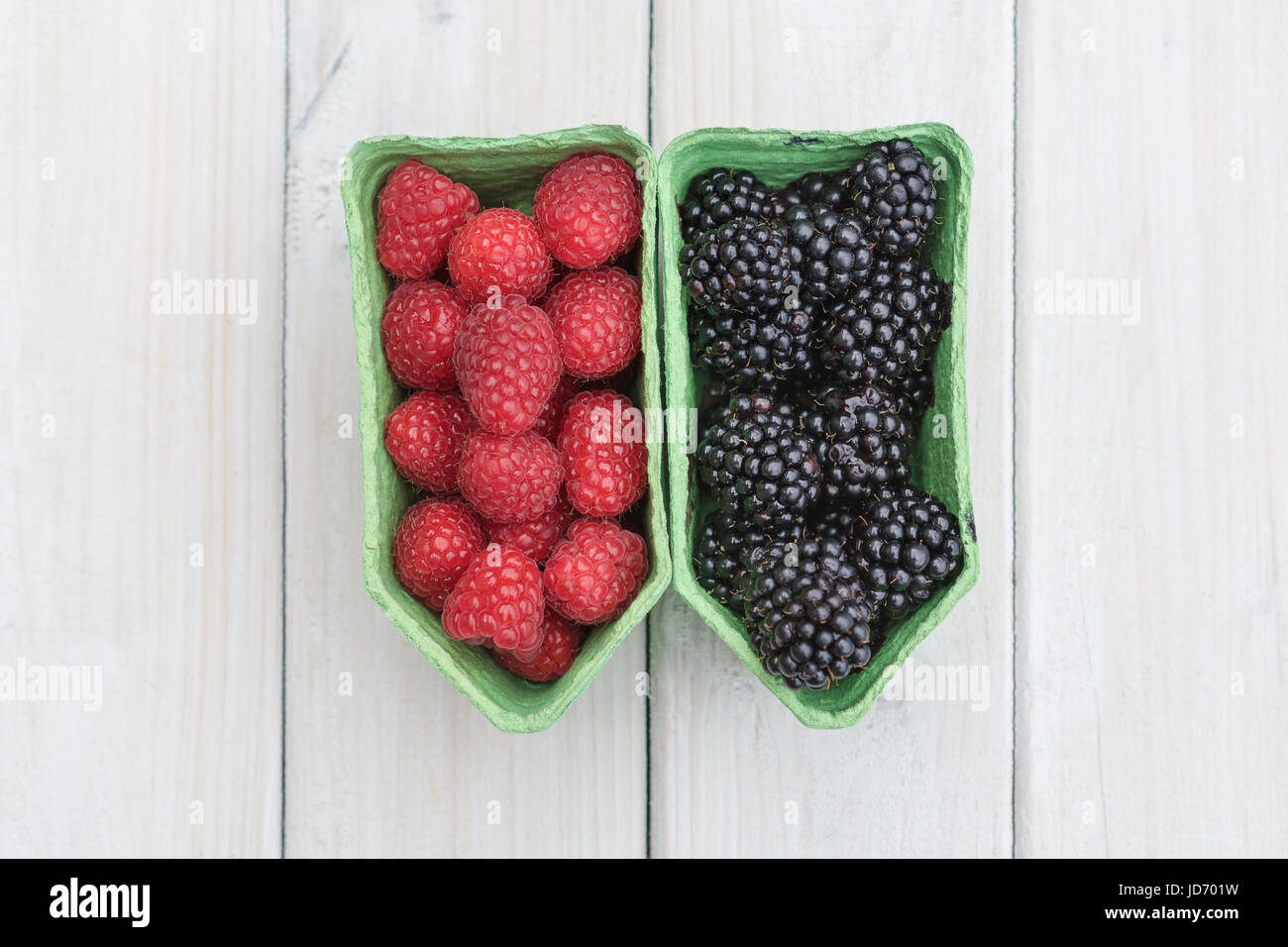 Raspberries and blackberries in a separate cardboard box on a white ...