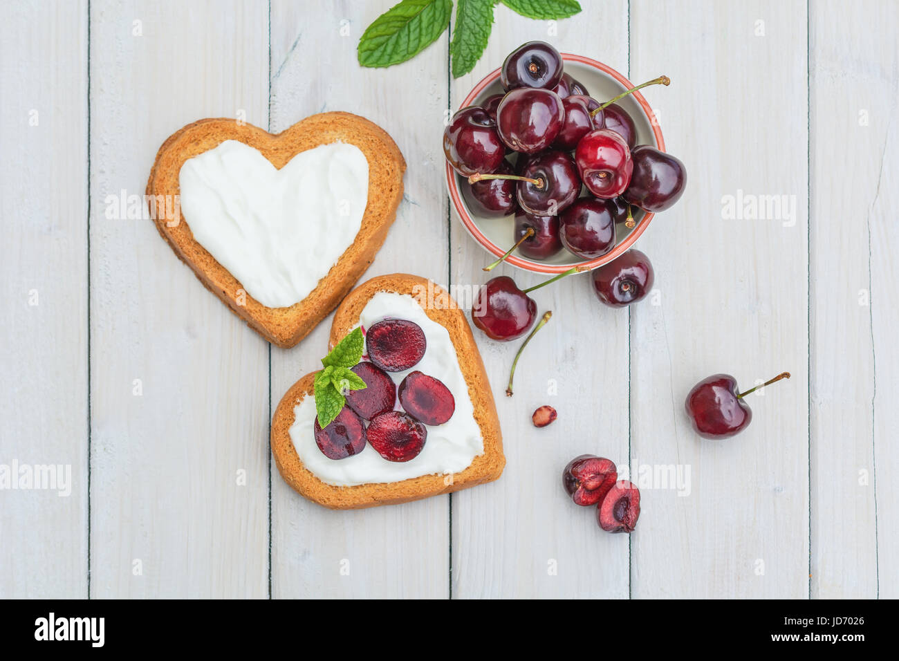 Bowl filled with cherries and heart shaped biscuits spread with quark ...