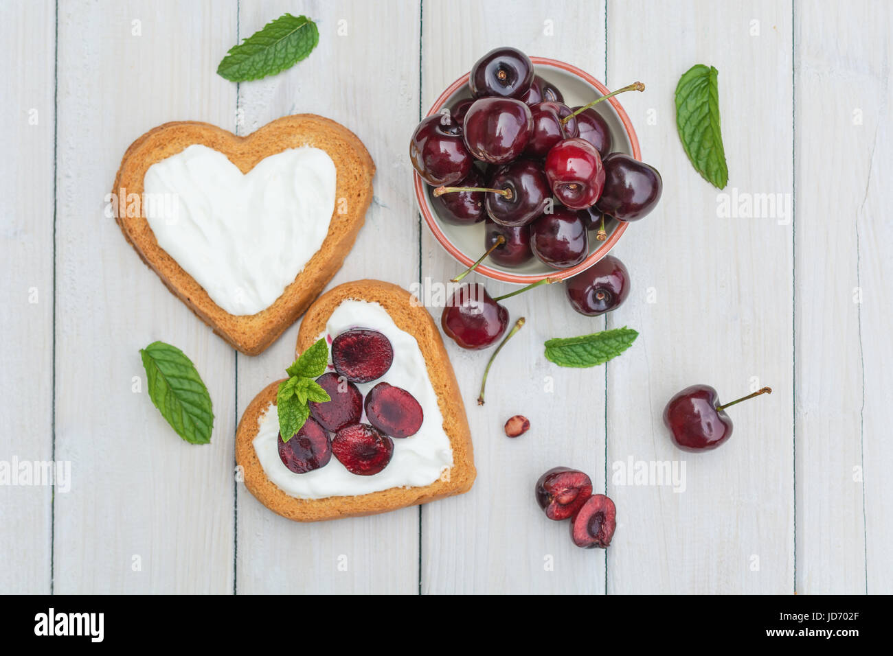 Bowl filled with cherries and heart shaped biscuits spread with quark ...