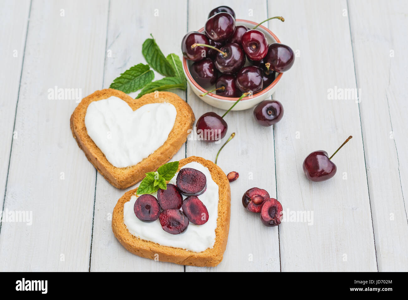 Bowl filled with cherries and heart shaped biscuits spread with quark ...