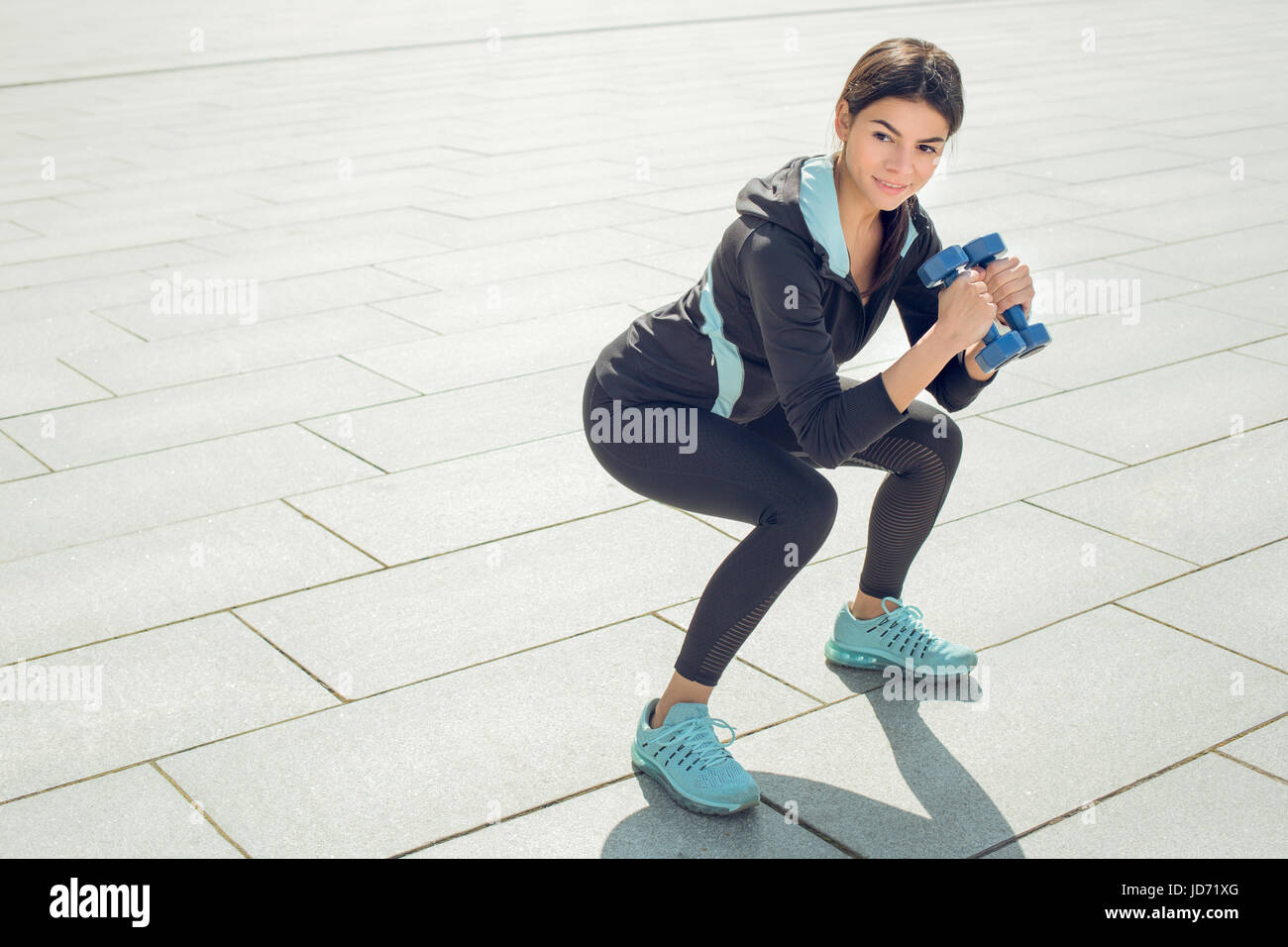 Young femaleactive exercise workout on street outside with dumbbells ...